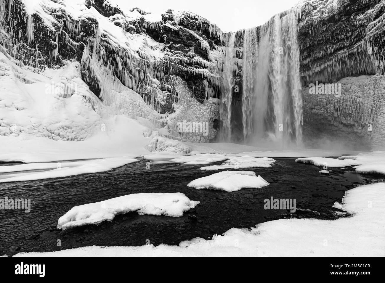 Skogafoss waterfall with icy and snowy rock face, black and white photo ...