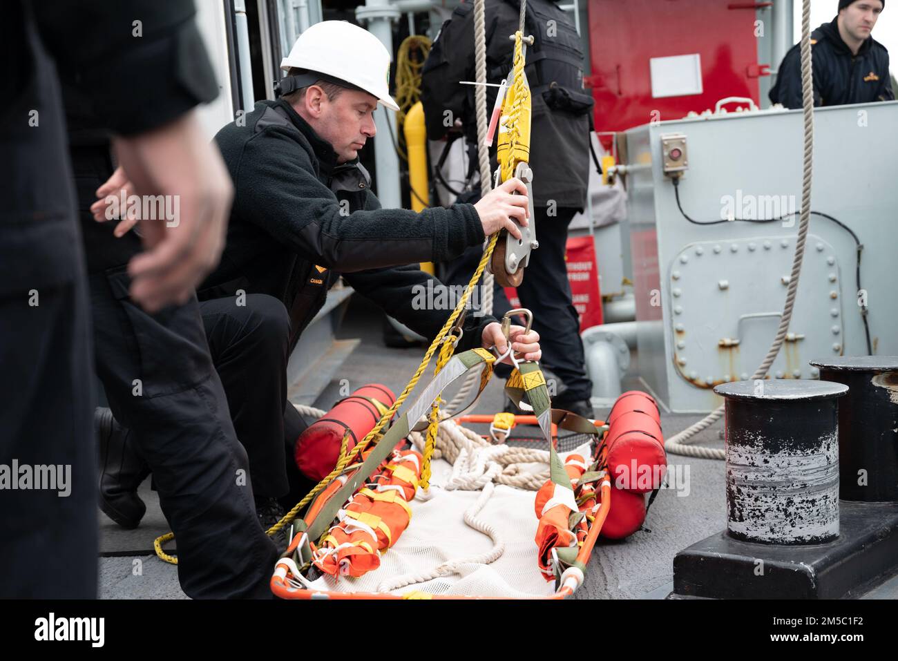 Petty Officer Second Class Lance Ingeberg attaches a stokes litter to ...