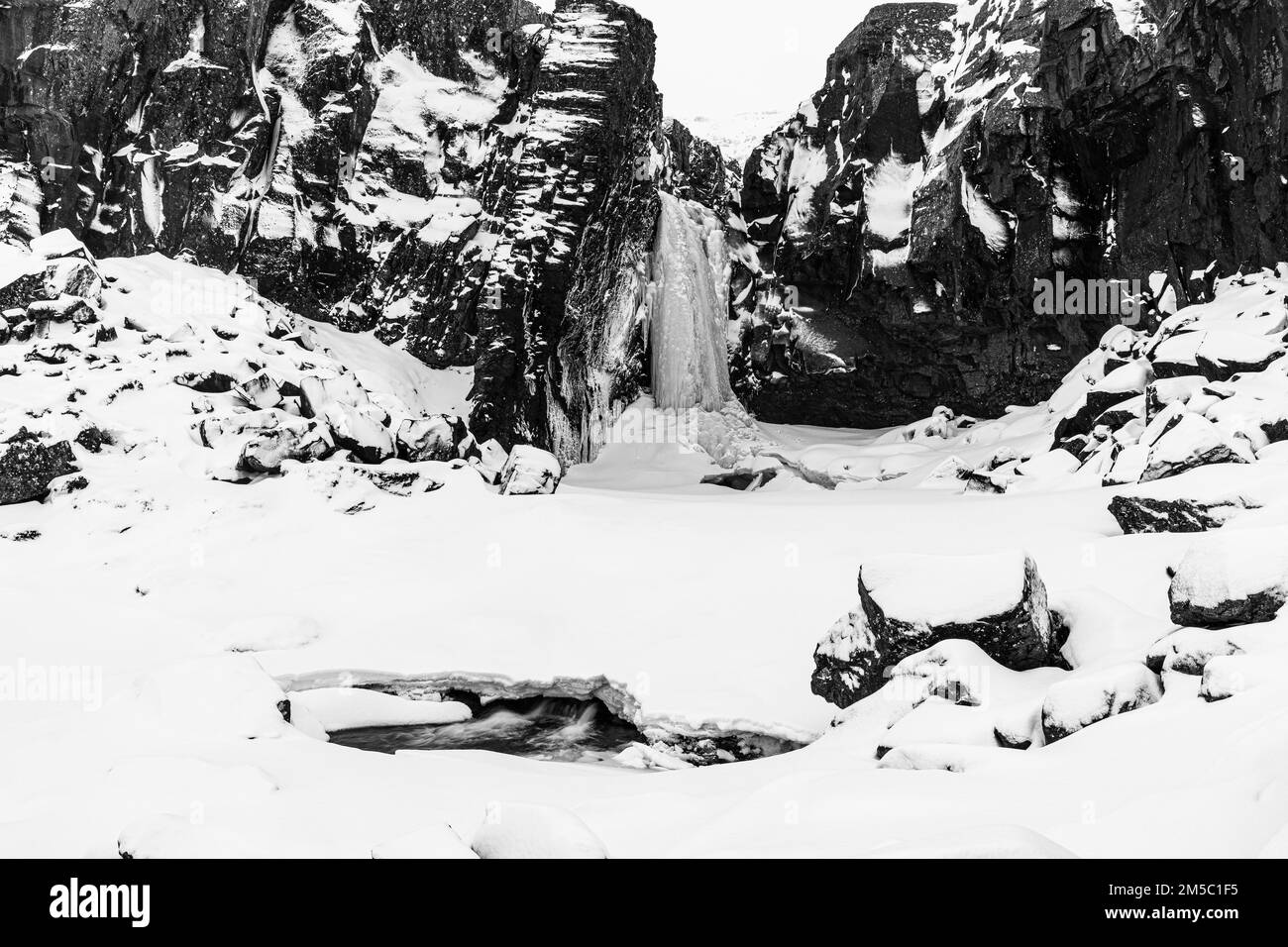 Frozen waterfall, Folaldafoss, snowy rock face and snowy landscape ...