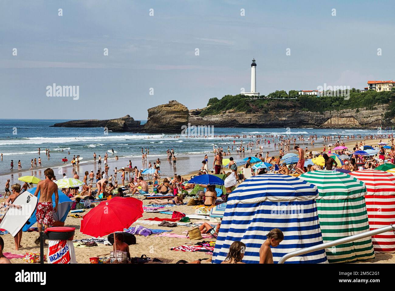 View of coastline with lighthouse and crowd, tourists on the beach ...