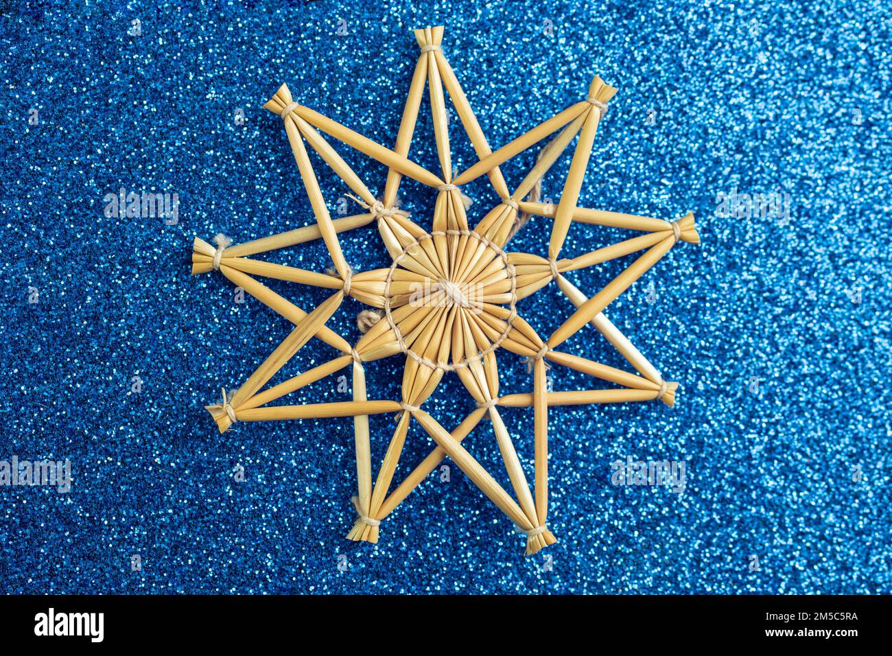 Christmas star decoration made with golden straws and thread on blue ...