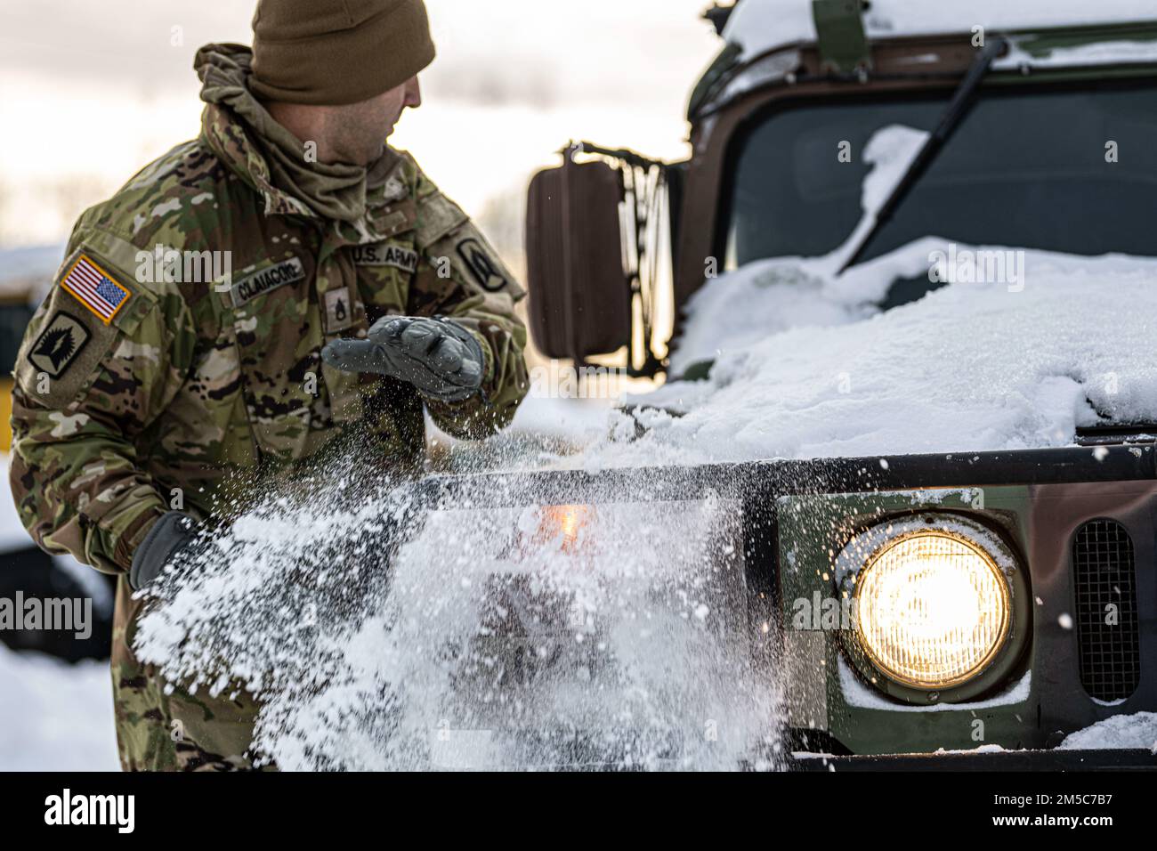 A U.S. Army soldier brushes snow off of an unloaded Humvee in ...