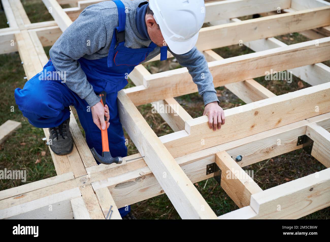 Man worker building wooden frame house on pile foundation. Carpenter ...