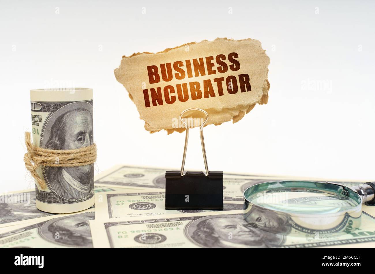 Business concept. Among the dollars lies a magnifying glass and there is a clip and a cardboard ...