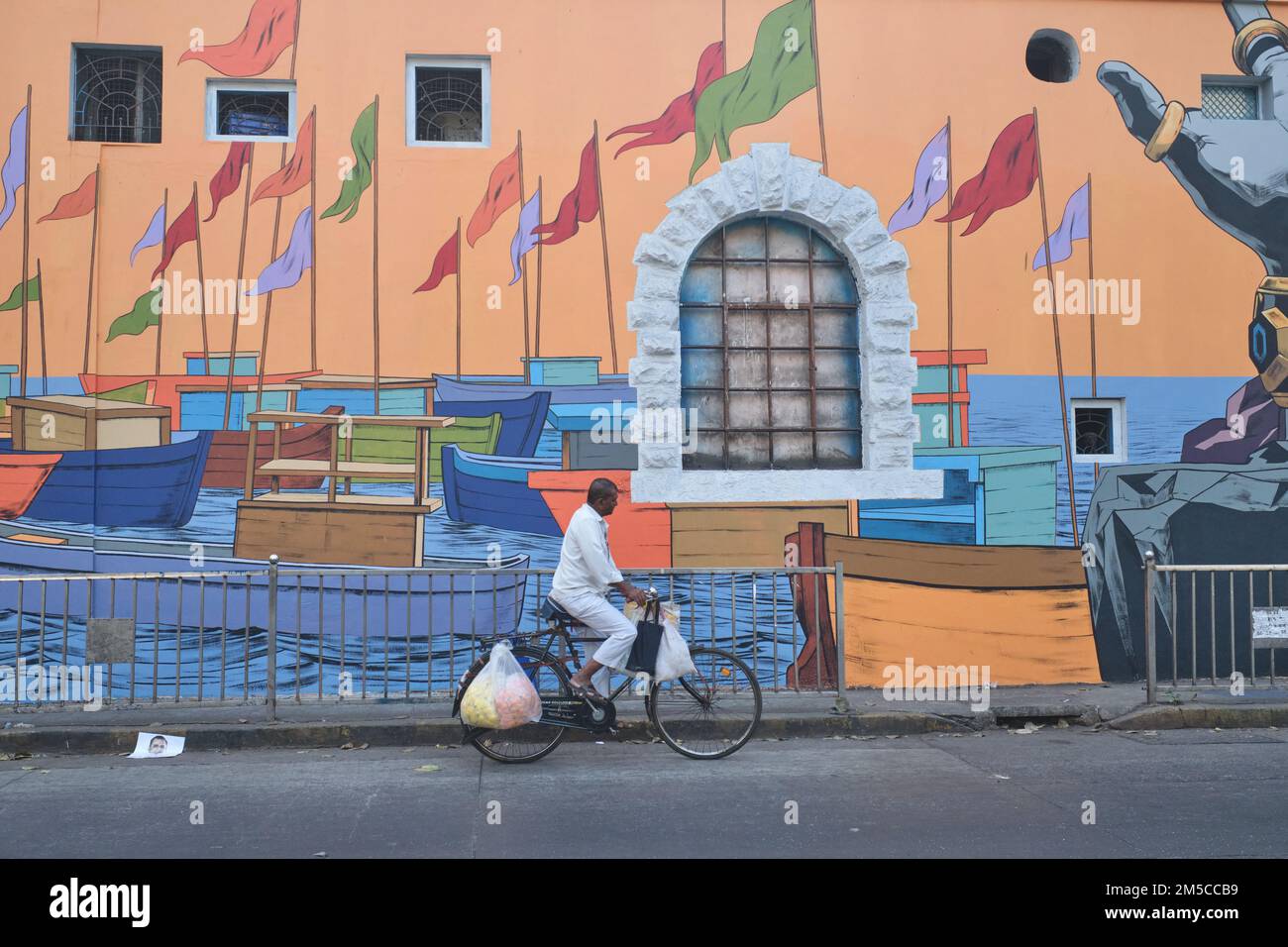 A cyclist passes a colorful wall painting at Sassoon Docks, Colaba ...