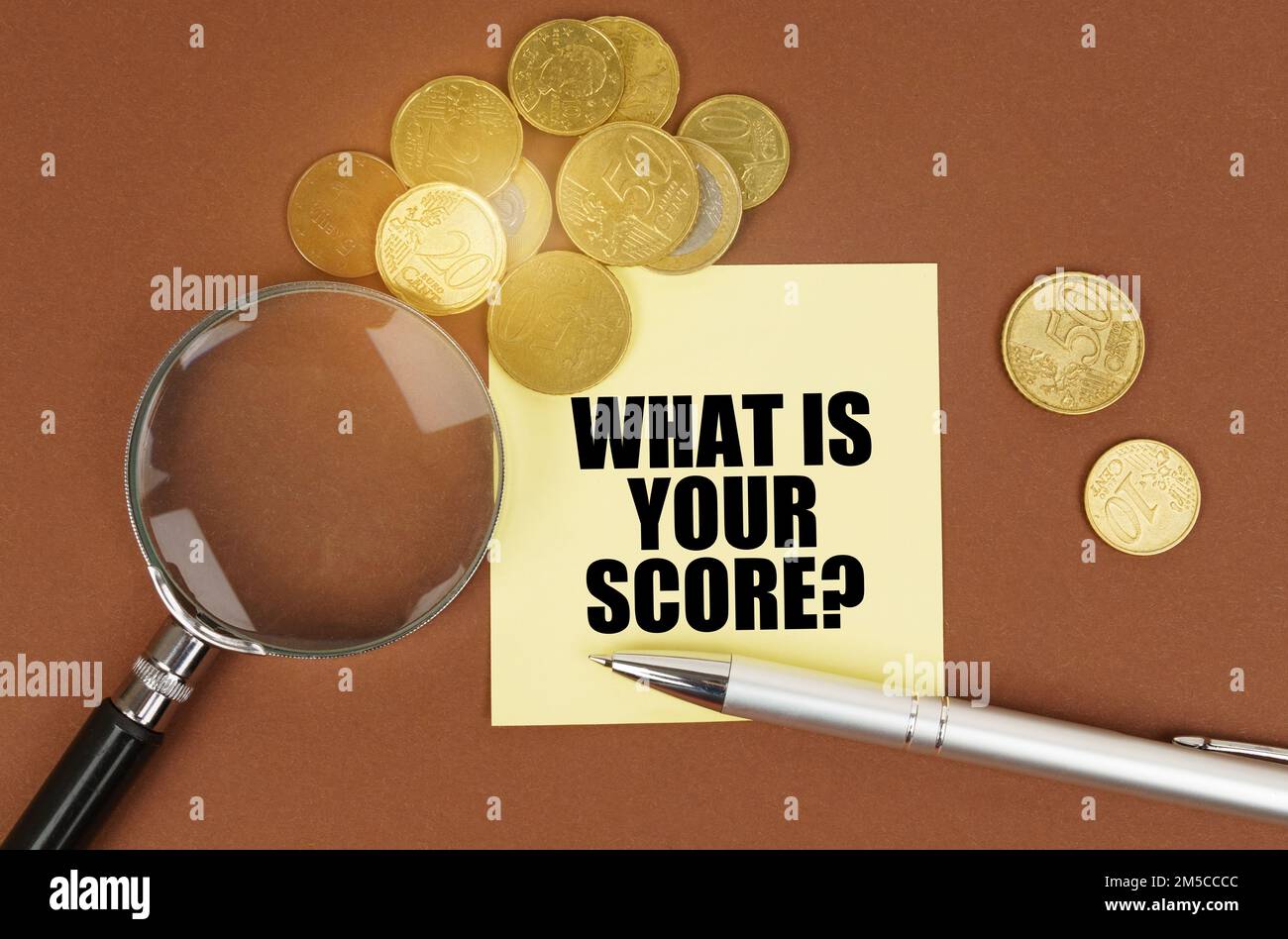 Business concept. On a brown surface are coins, a pen, a magnifying ...