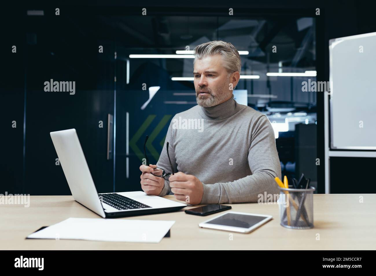 Serious thinking businessman inside office at work with laptop, senior ...