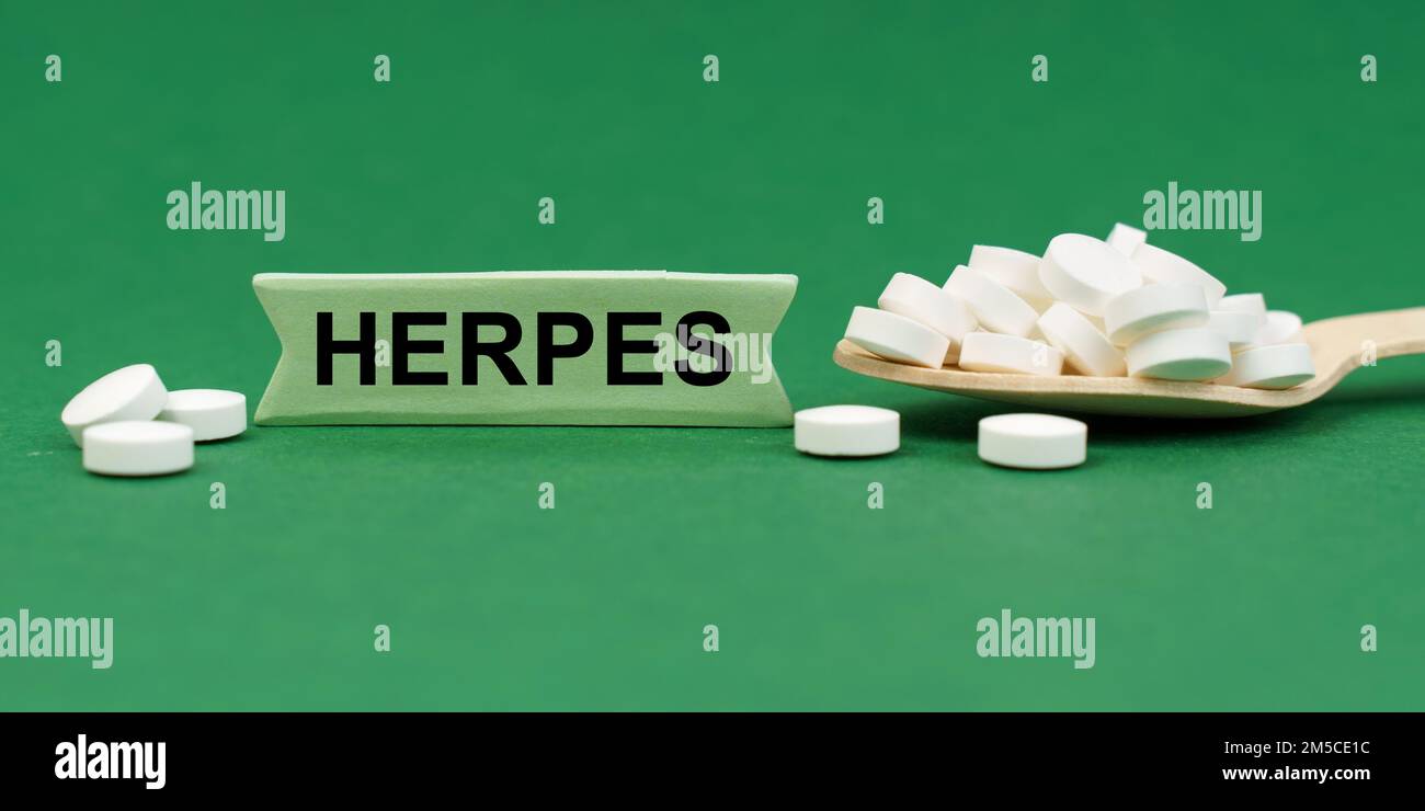 Medicine concept. On a green surface, a wooden spoon with pills and a ...