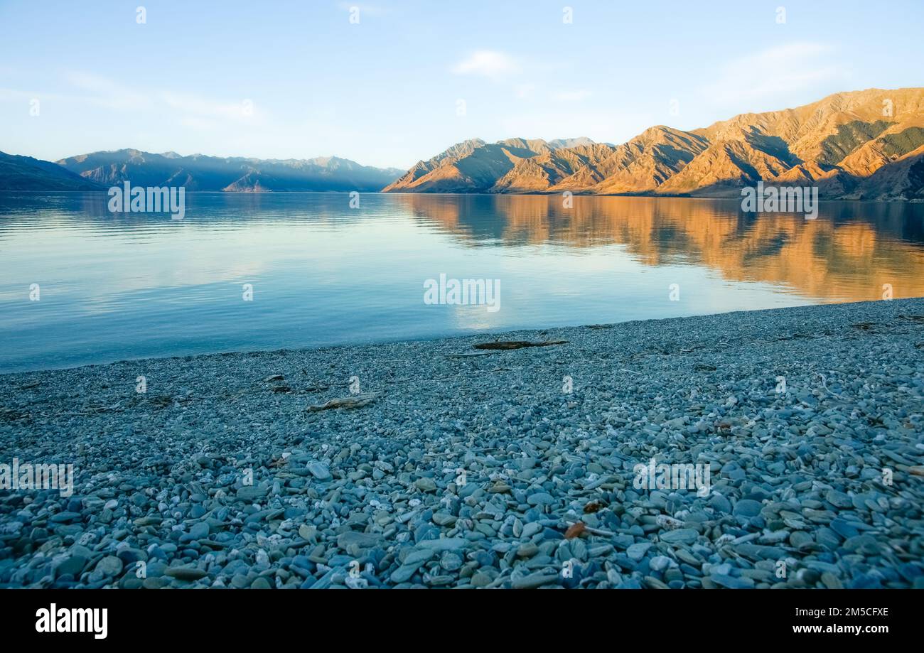 Peaceful Lake Wanaka in morning light surrounding hills and blue sky ...