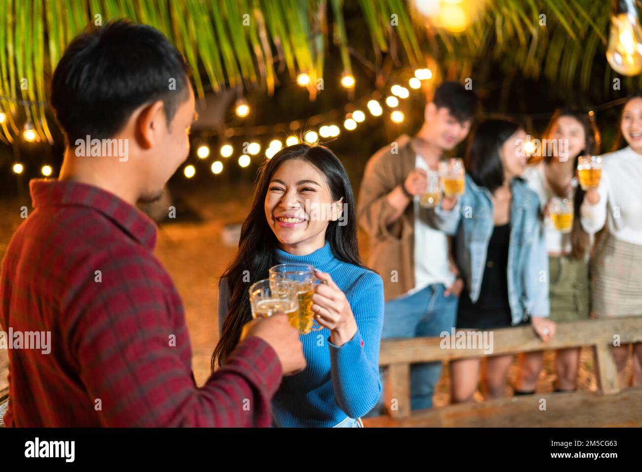 Happy couple drinking beer with friends at party Stock Photo - Alamy