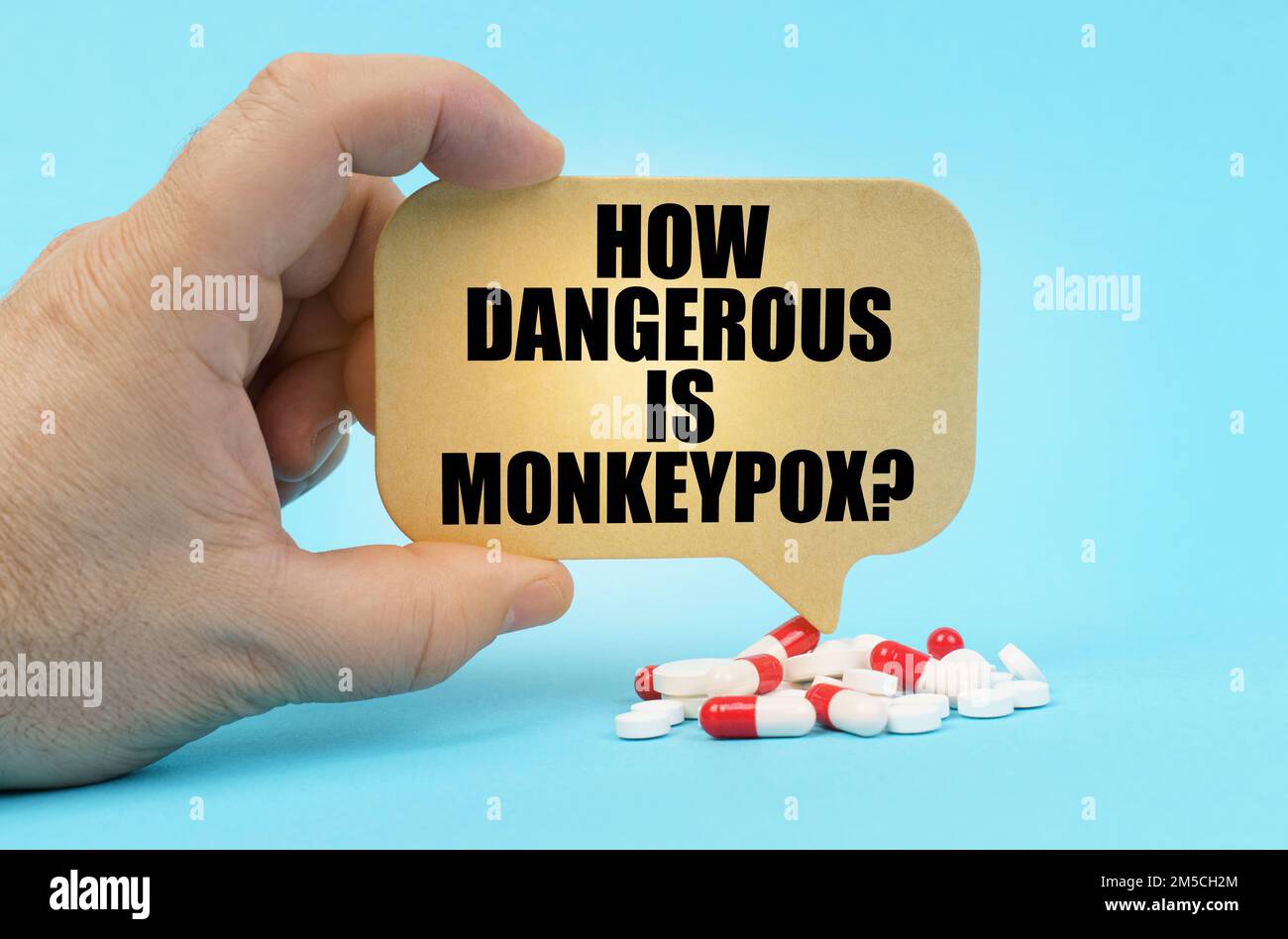 Medical concept. On a blue surface are pills in a persons hand, a sign ...