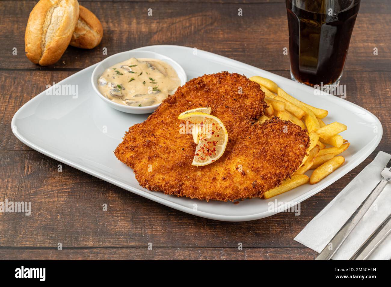 Chicken schnitzel with butter and potato salad on white porcelain plate ...