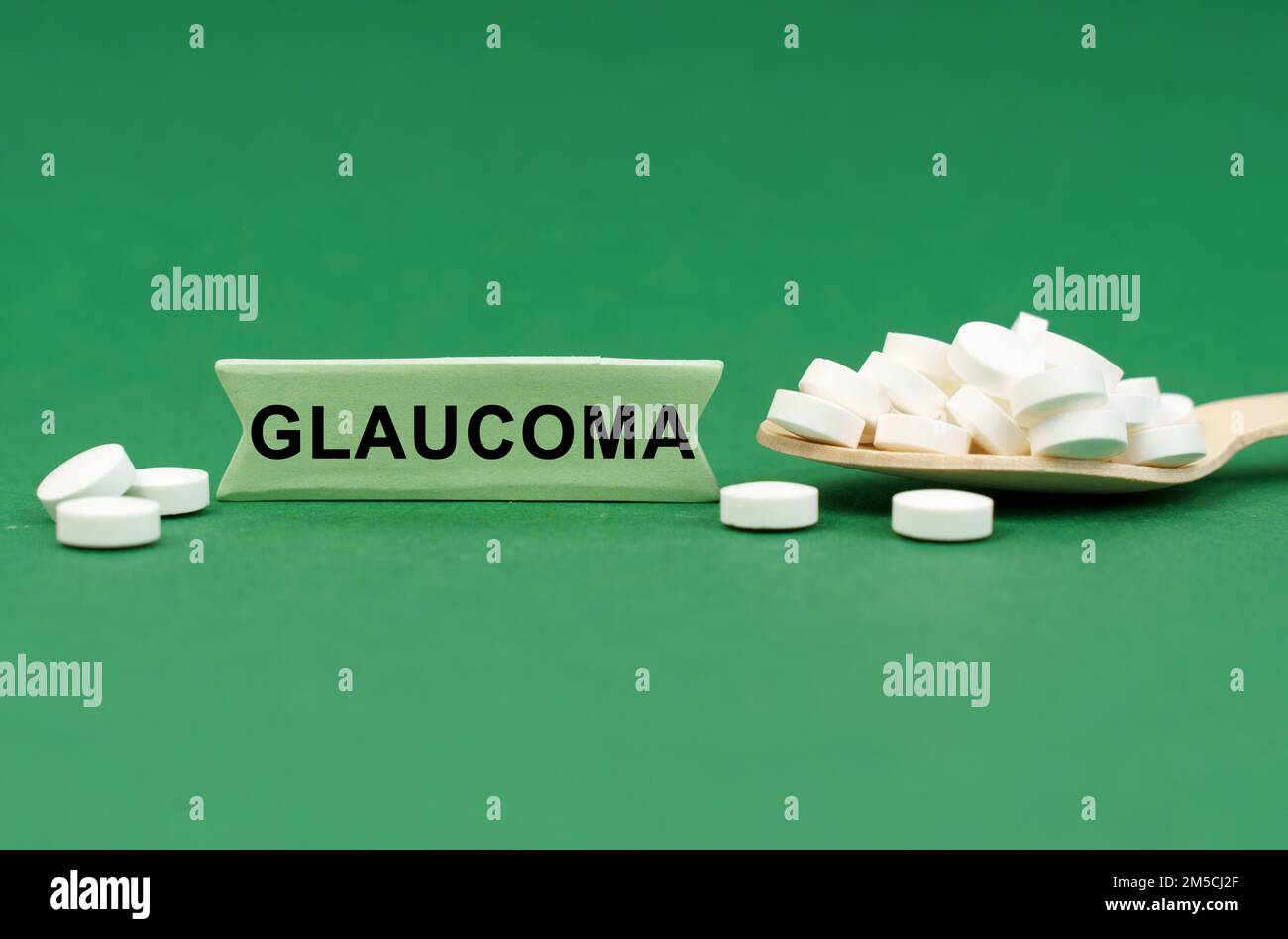 Medicine concept. On a green surface, a wooden spoon with pills and a ...