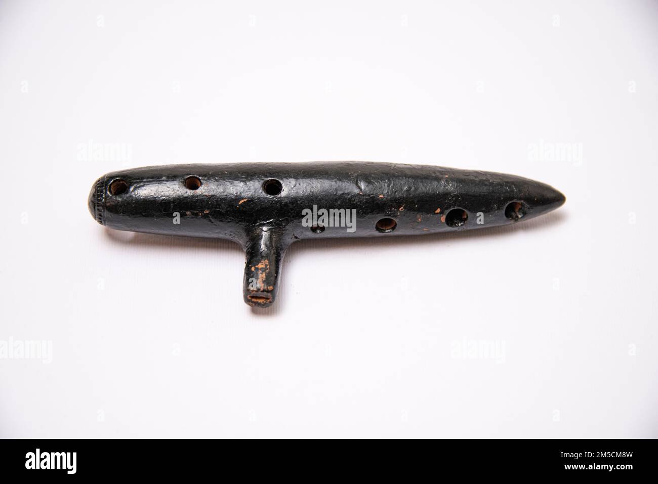 A closeup of an ocarina old wind musical instrument on a white ...