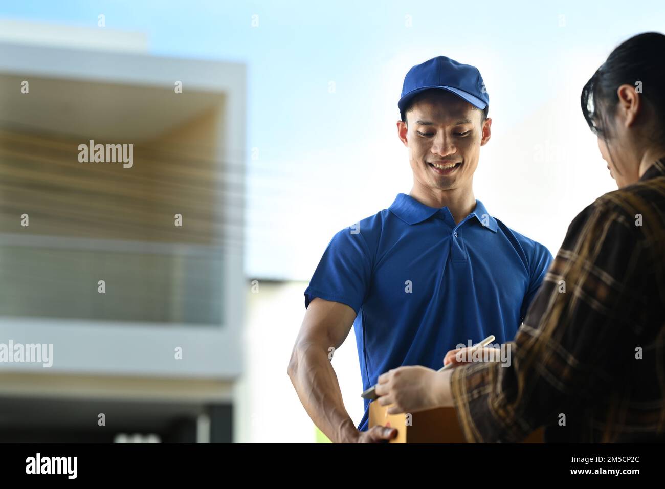 Friendly delivery man giving postal package to customer at doorway ...