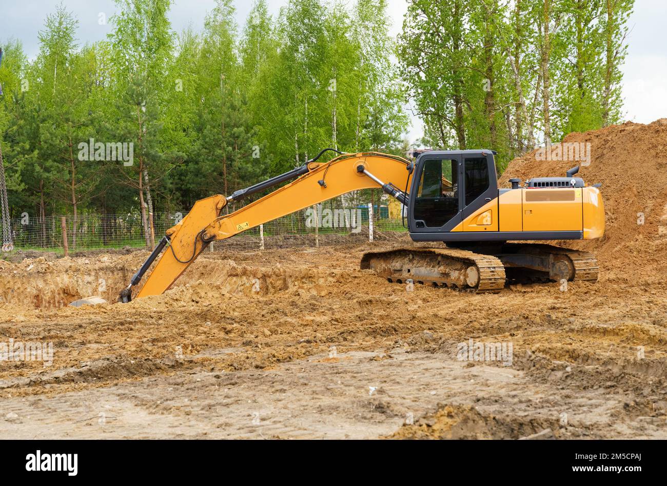 Building concept. An excavator is digging a pit for a house Stock Photo ...