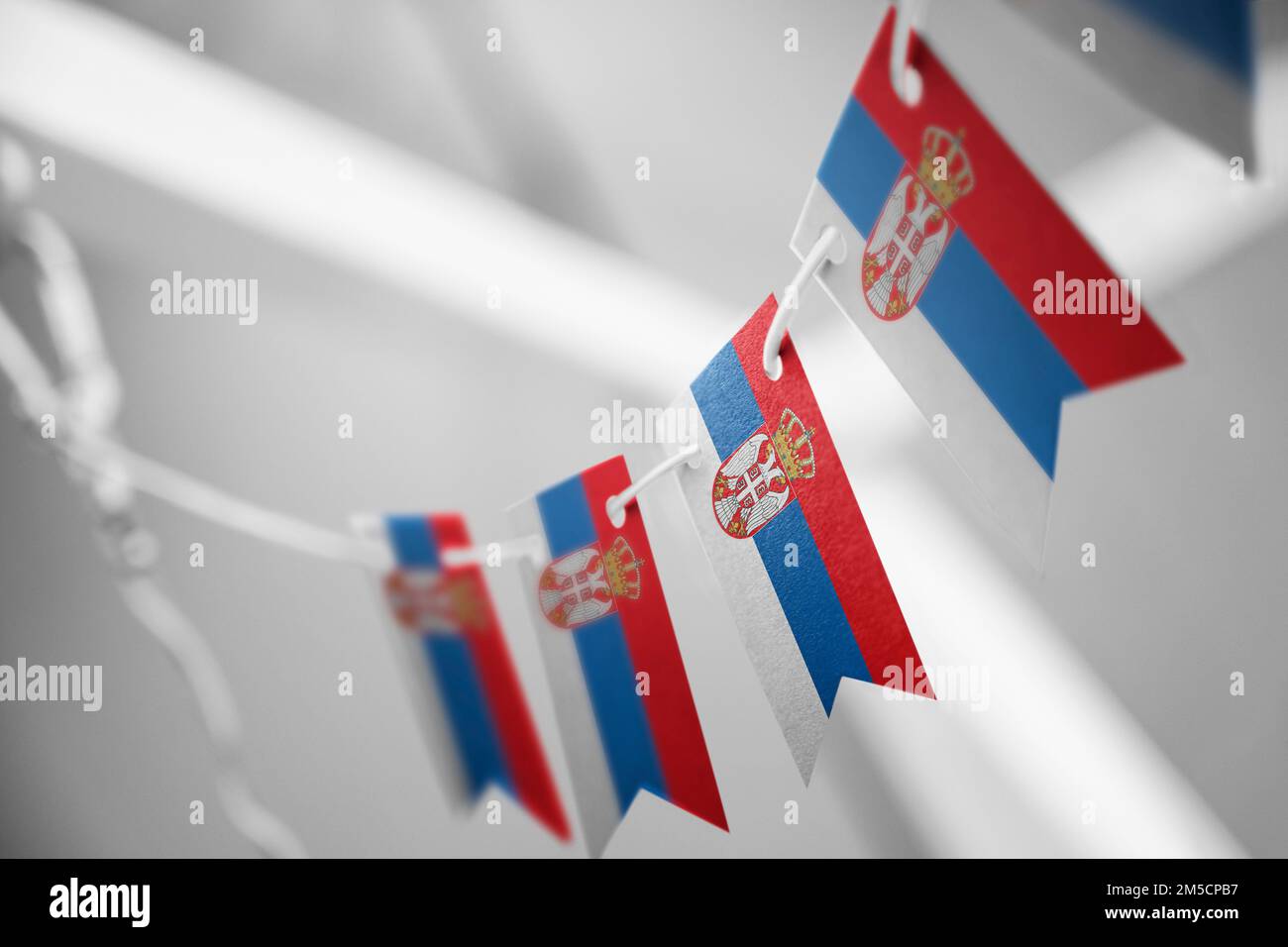 A garland of Serbia national flags on an abstract blurred background ...