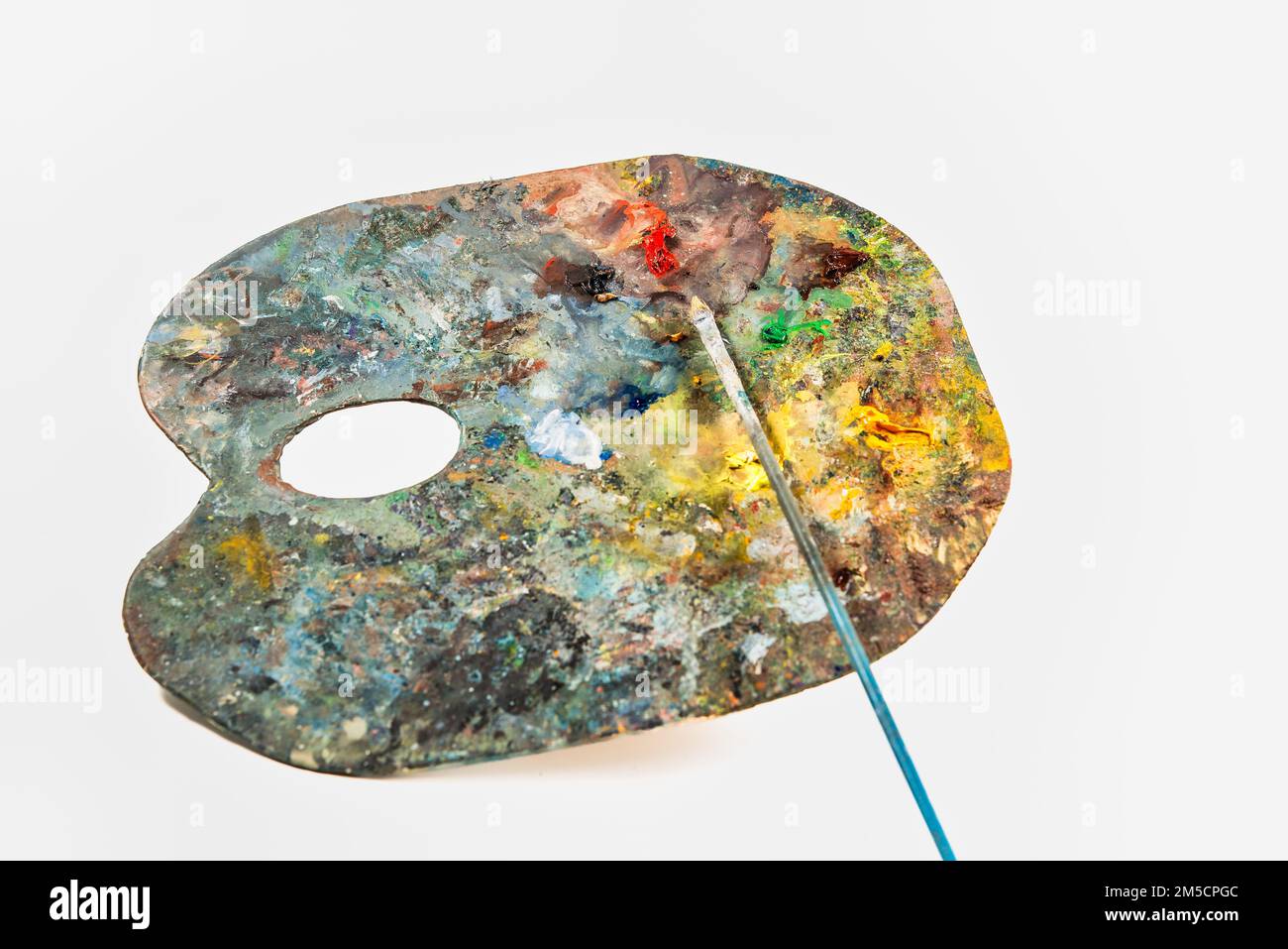 A painter's palette and brush with lots of colors scattered on a white ...