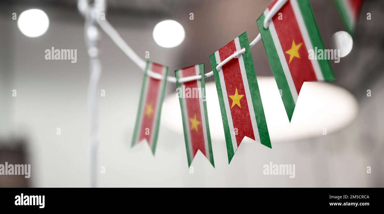 A garland of Suriname national flags on an abstract blurred background ...