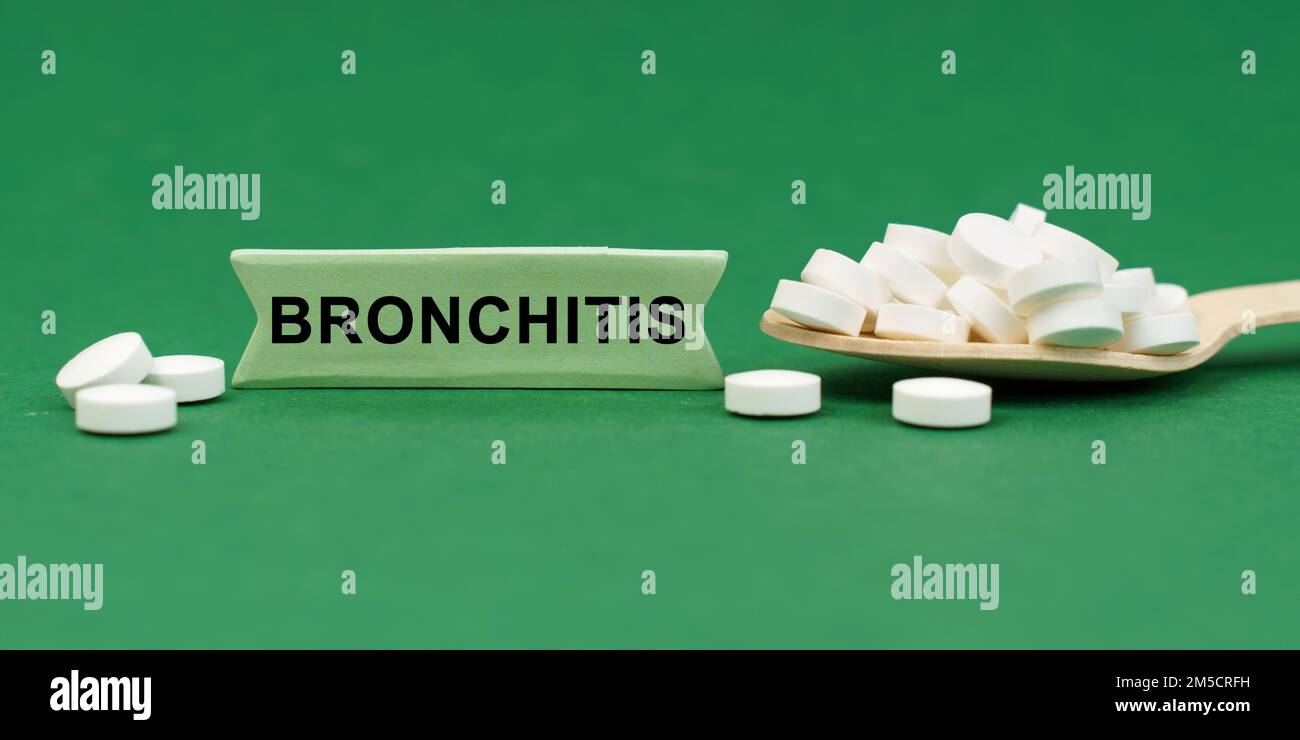 Medicine concept. On a green surface, a wooden spoon with pills and a ...