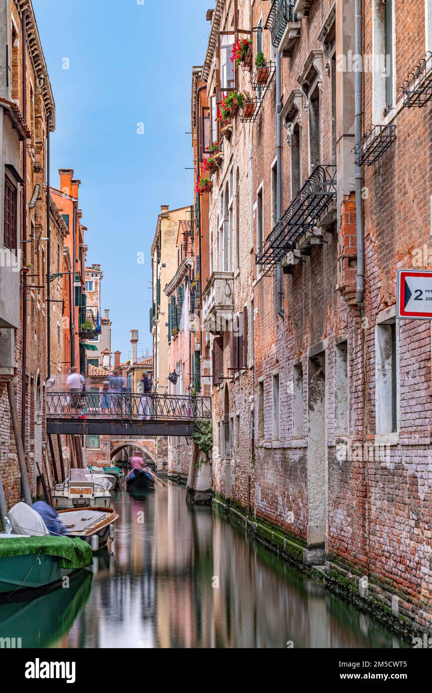 narrow canal in Venice with historic houses and a gate to enter the ...