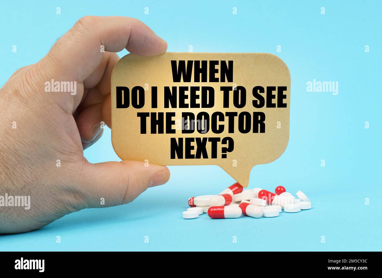 Medical concept. On a blue surface are pills in a persons hand, a sign ...