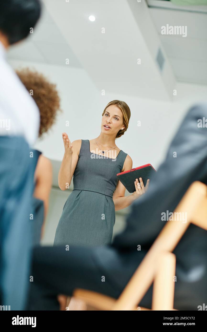 Explaining her strategy to the team. a businesswoman holding a digital ...