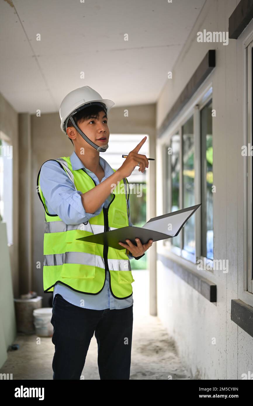 Asian man inspector in safety helmet and vest holding document ...