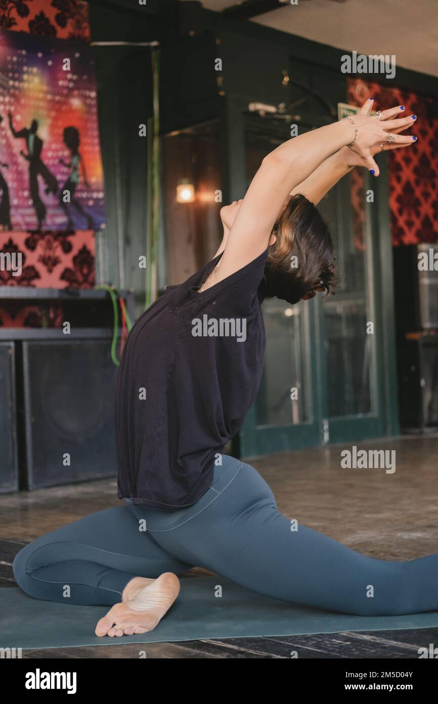 New yoga teacher woman doing a one-legged king pigeon pose (eka pada kapotasana) with a backbend ...