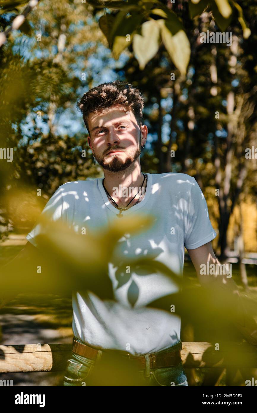 A vertical shot of a caucasian man near a wooden fence surrounded by ...