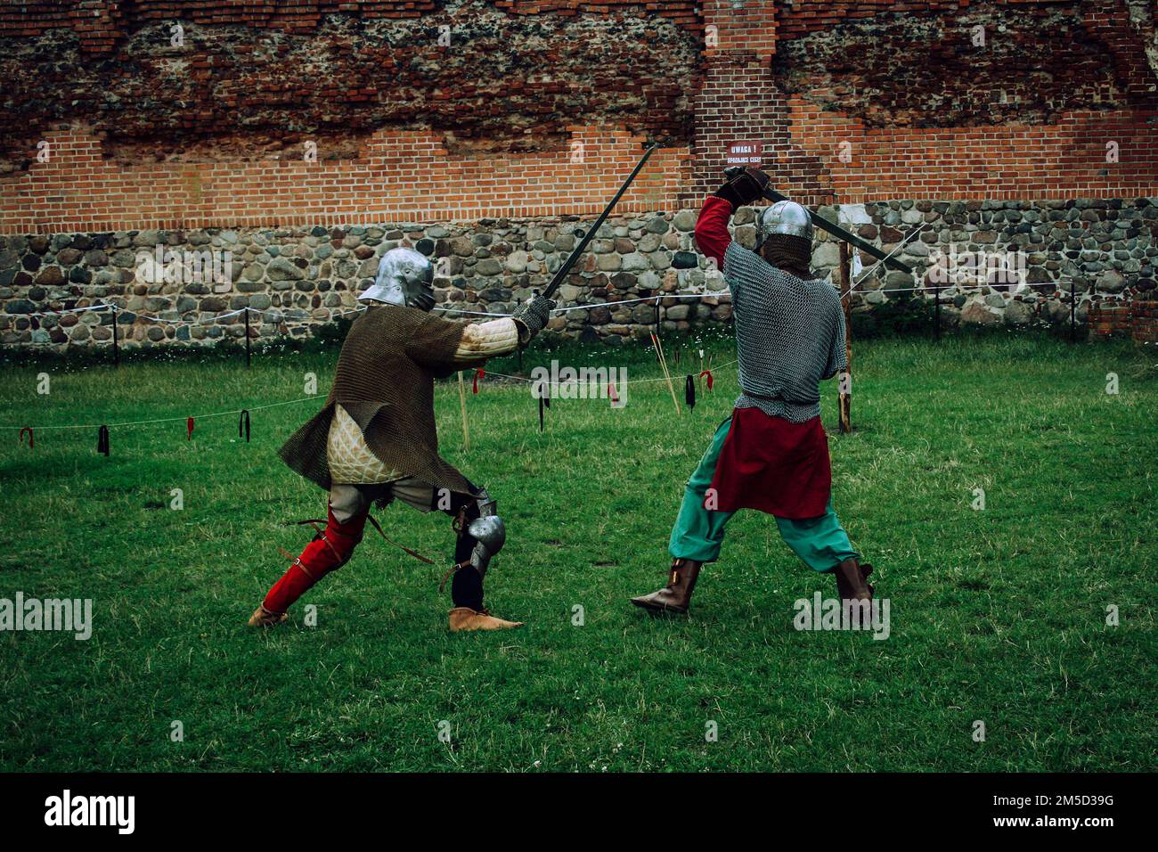 Sword fight of two knights in helmets and chain mail armor in scenery of medieval castle Stock ...
