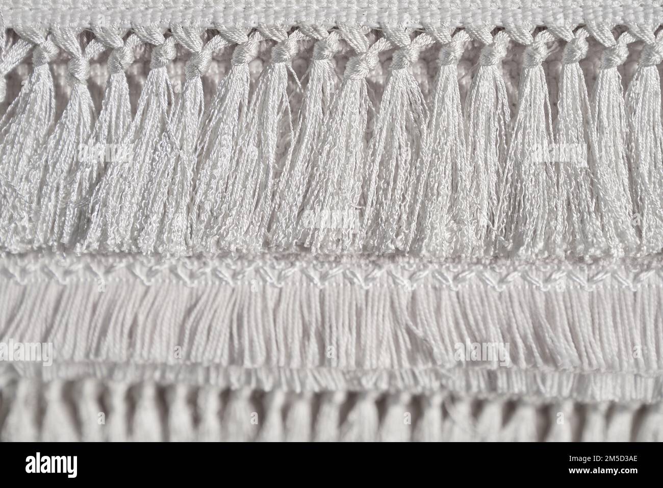 Light cotton fringe on edge of white, woven carpet. Close up of rug ...