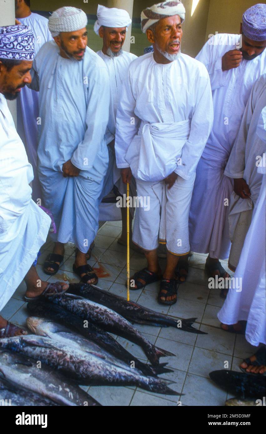 Oman, Nizwa. Omani men in traditional robes discuss the fresh catch at ...