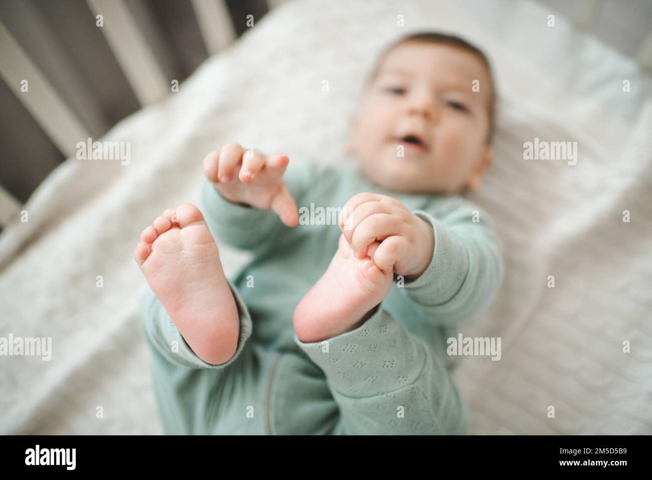 Funny smiling infant baby boy wake up in bed crib look at camera over ...