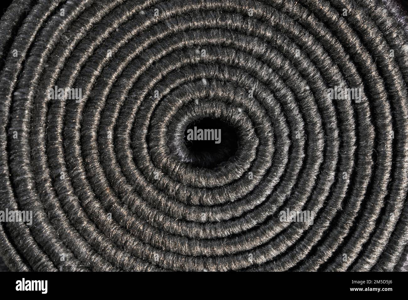 Textured backdrop of tight rolled up grey carpet edge, with void in ...