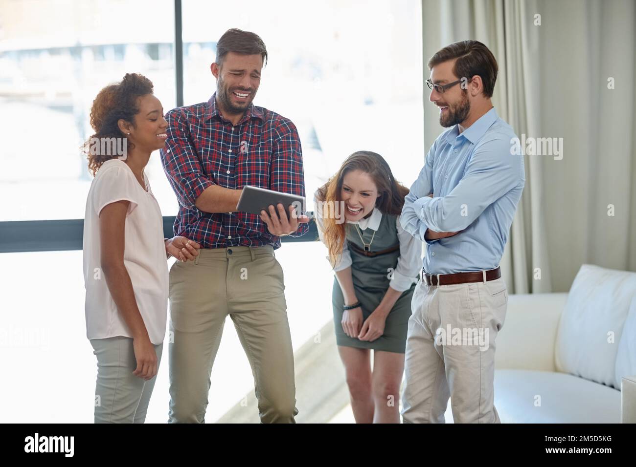 Work meets play. a group of colleagues laughing while using a digital tablet together at work ...