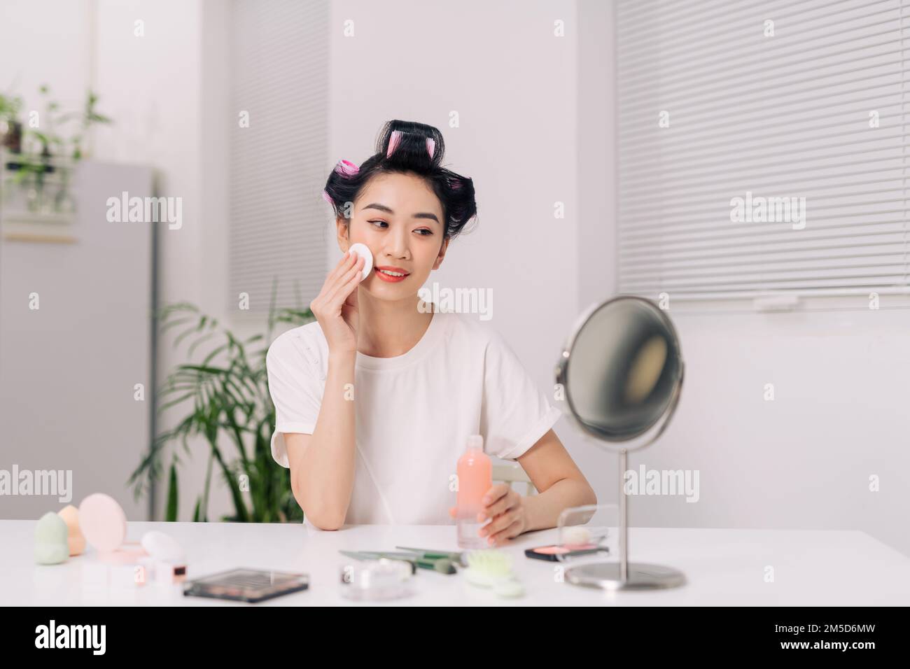 Young happy woman removing makeup from her face enjoying her skin and ...