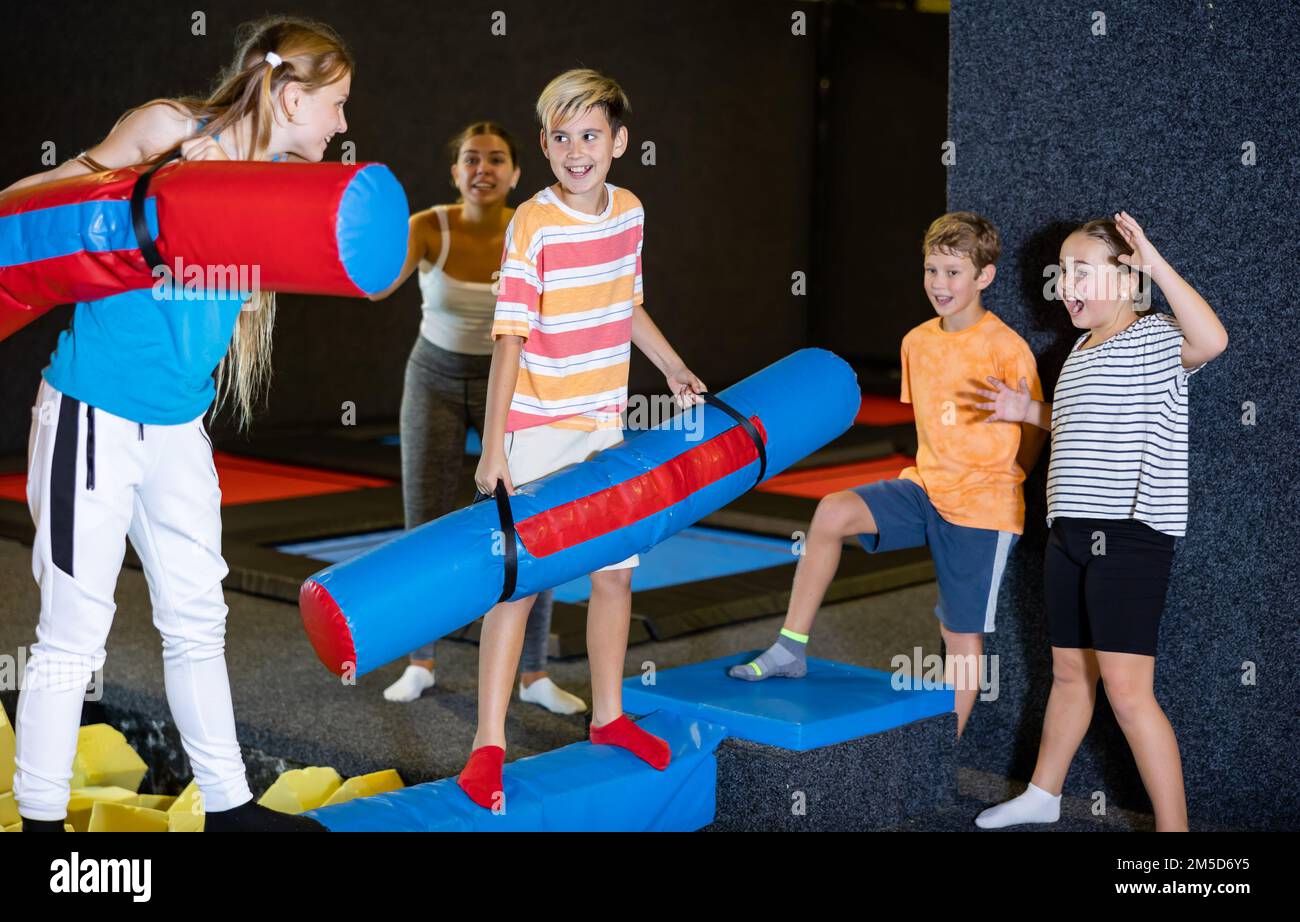 Cheerful school-age boy and teen girl friends having fun on inflatable ...