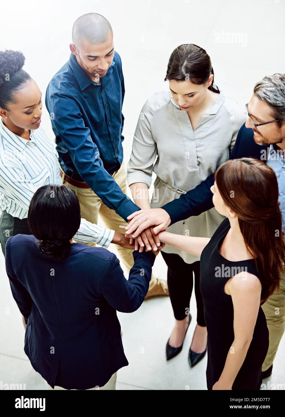 Less me, more we. High angle shot of a group of businesspeople piling ...