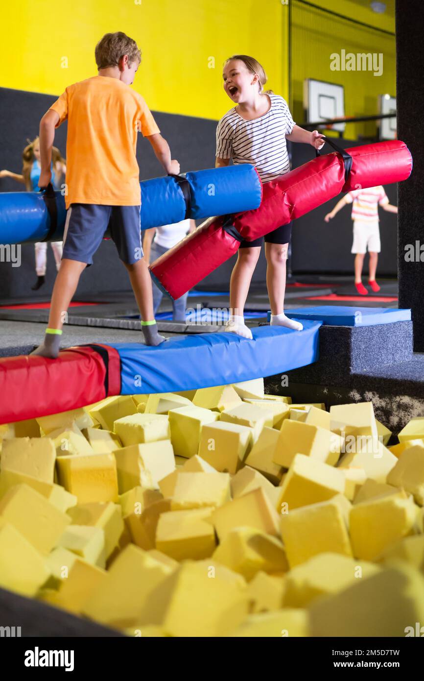 Excited children boy and girl having funny wrestling by inflatable logs ...