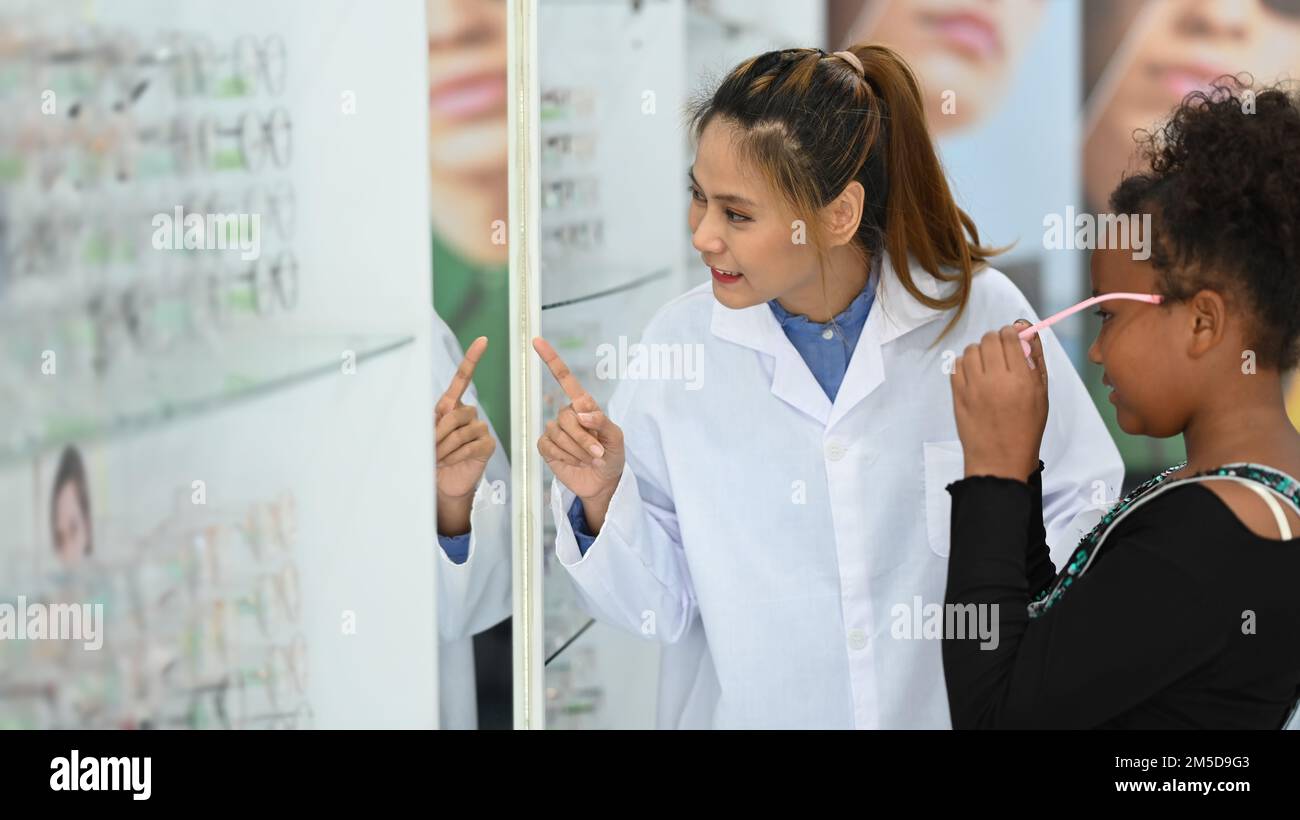 Optician helping African American girl choosing spectacles glasses. Eye ...