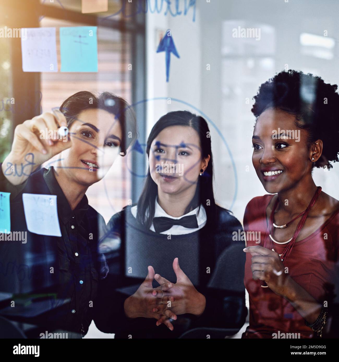 Leave the planning to them. three businesswomen working on a glass wall ...