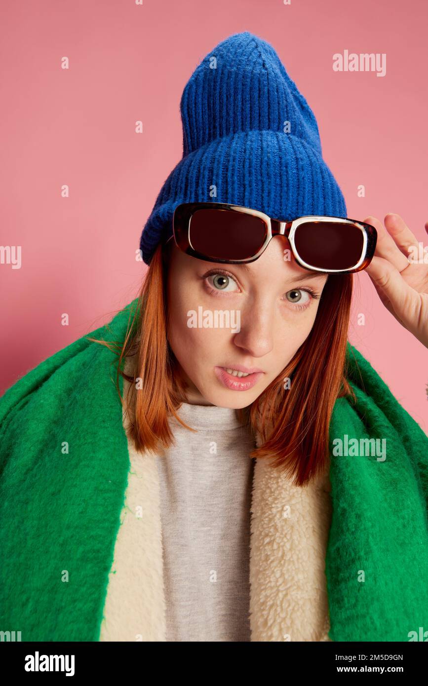 Portrait of stylish young girl in sunglasses, blue hat, green scarf and ...