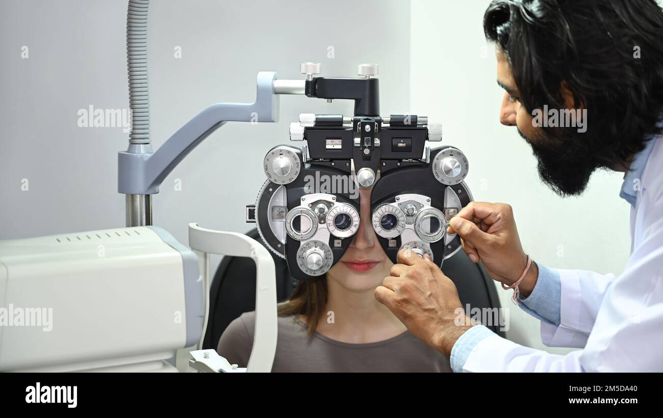 Young female patient checking eye vision with phoropter eyesight ...