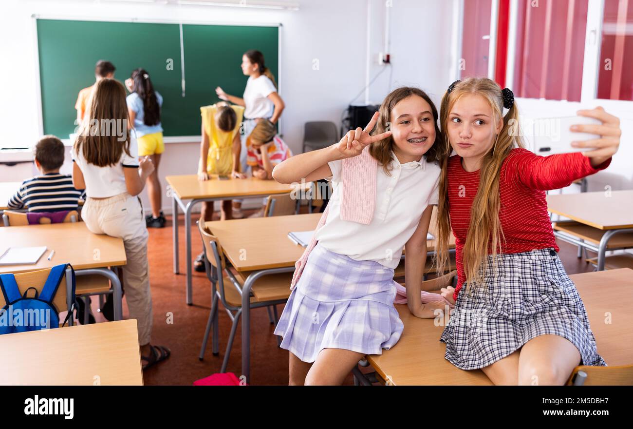 Two girls taking selfies in classroom during recess Stock Photo - Alamy