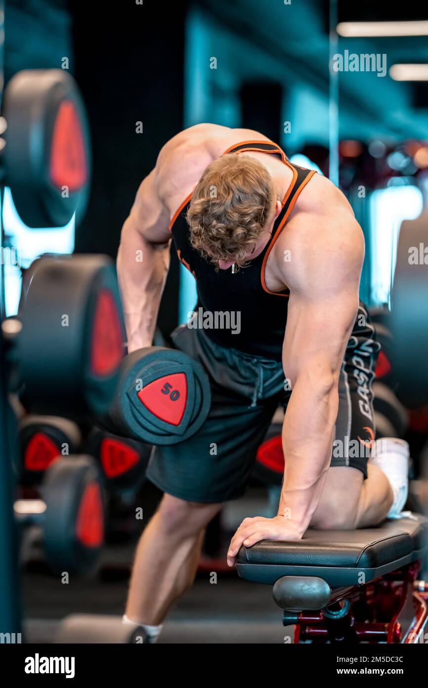 One-arm dumbbell pull-ups in a forward bend with knee support Stock ...