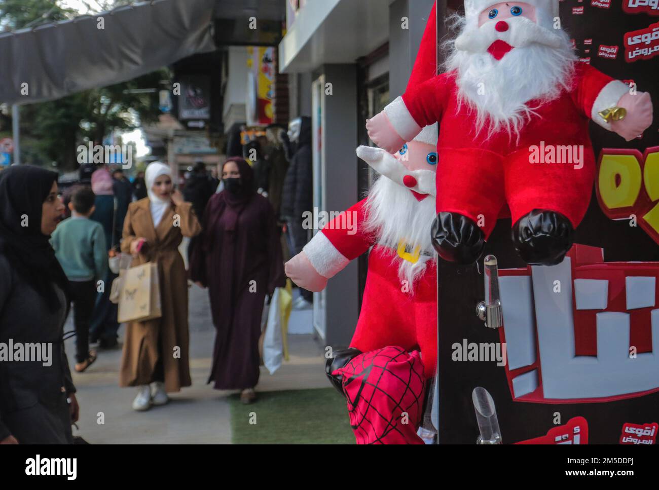 Palestinians walk past a gift shop and Santa Claus toys in Gaza City ...