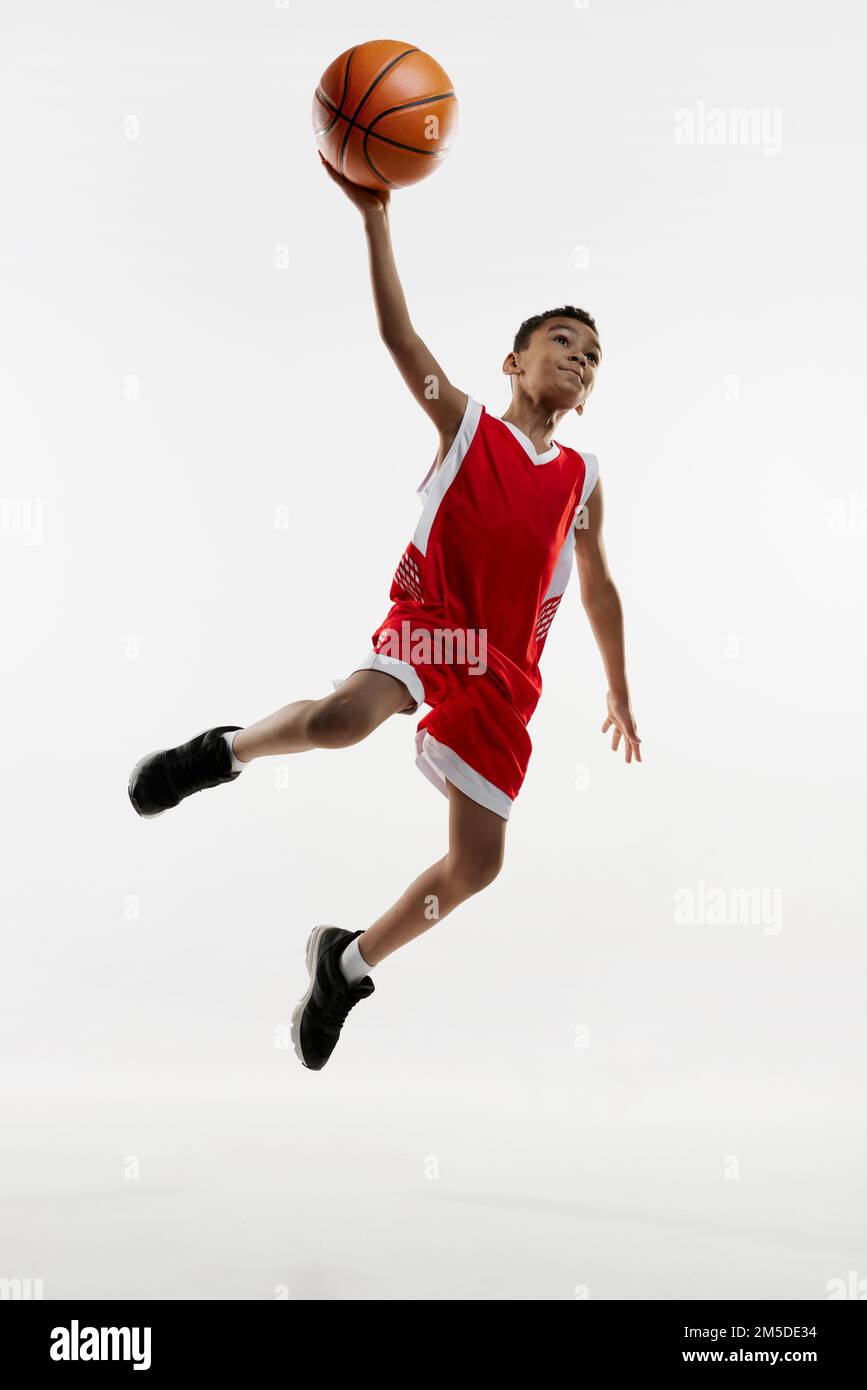 Portrait of boy in red uniform training, playing basketball, throwing ...