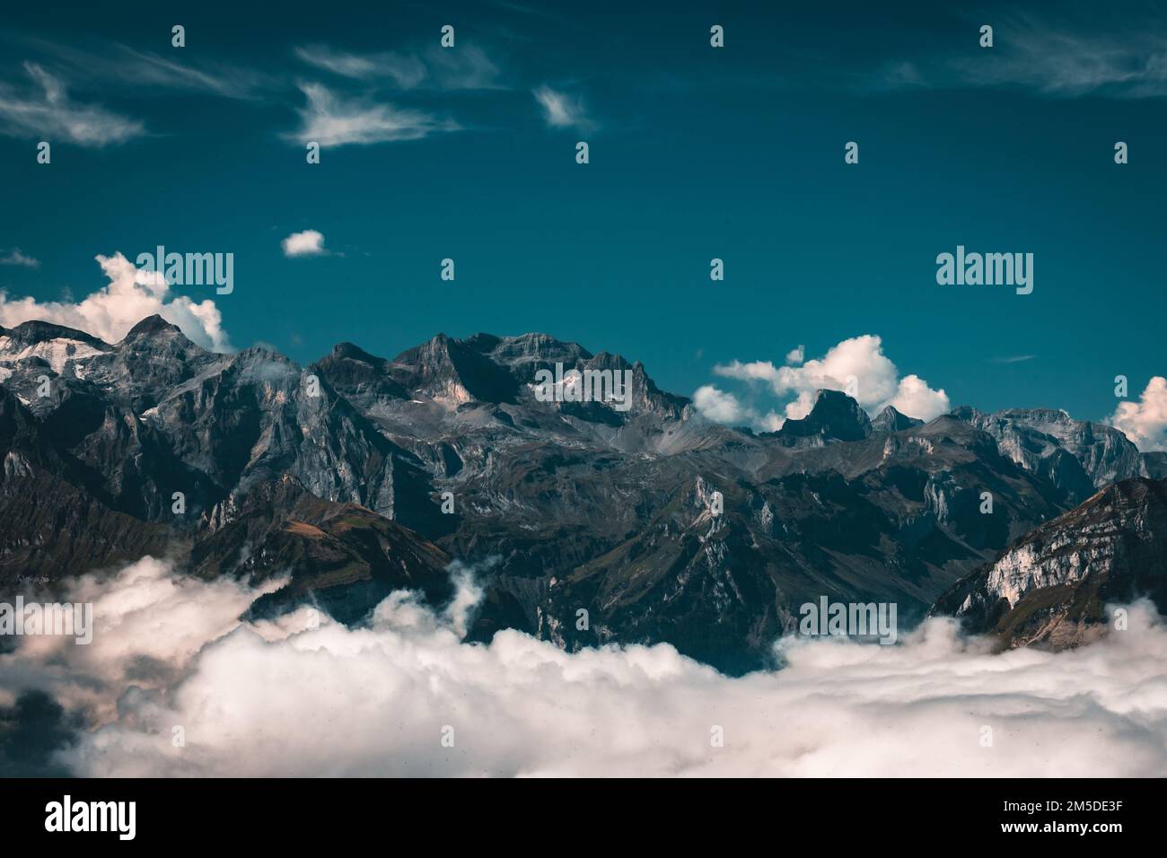 A scenic view of huge rocky mountains enveloped in white clouds in a ...