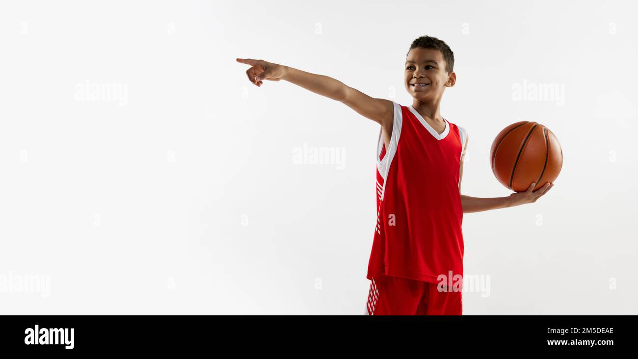 Portrait of boy in red uniform, basketball player posing with ball over ...